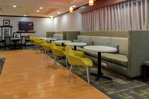Um saguão de hotel com áreas de estar, uma televisão e quadros nas paredes.