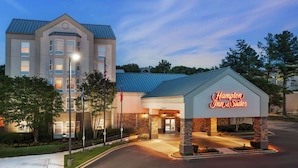 Um hotel Hampton Inn & Suites com design moderno, apresentando uma entrada notável e fachada bem iluminada.