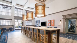 Uma sala de jantar espaçosa com uma mesa de madeira comprida, diversas cadeiras e luminárias de vime suspensas.