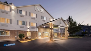 Hotel com fachada de pedra, entrada coberta e placa de estacionamento para deficientes.