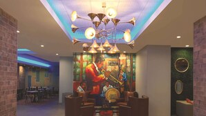 Um saguão com um mural de uma banda de jazz, um lustre moderno e paredes de tijolo.