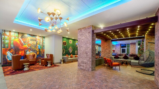 Um hall amplo com piso em padrão herringbone, um grande mural de músicos e um lustre moderno.
