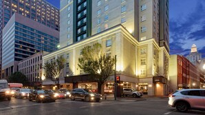 Um hotel com fachada moderna, vários andares e uma entrada destacada com sinalização iluminada.