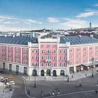 Um edifício grande e histórico, com fachada simétrica, janelas em arco e uma entrada central.