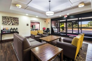 Um hall de hotel com assentos de couro, um espaço para café e vista através de grandes janelas.