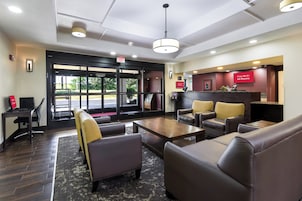 Um saguão de hotel com assentos, balcão de recepção e vista para o exterior.