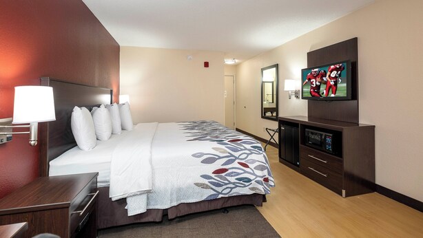 Quarto de hotel com cama, televisão, escrivaninha e micro-ondas.
