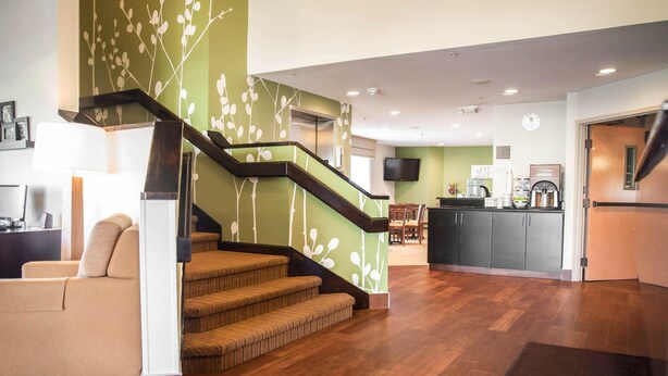 Um hall de hotel moderno com uma escadaria, um balcão de recepção e uma área de cozinha.