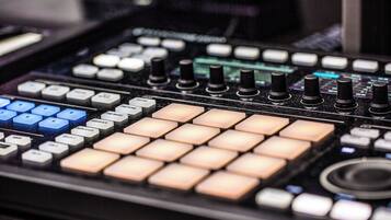 Close-up de um mixer de DJ com vários botões, controles deslizantes e botões.