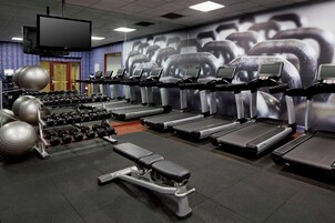 Academia com esteiras, halteres e bolas de exercício.