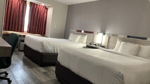 Quarto de hotel com duas camas, uma escrivaninha e uma cadeira.