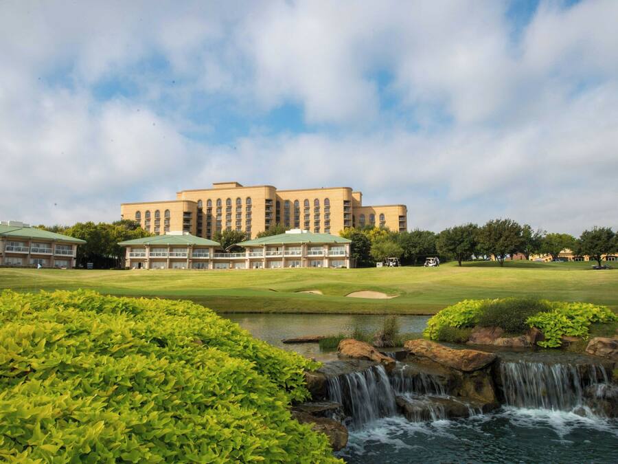 Um hotel grande com vários edifícios, campo de golfe e uma cascata.