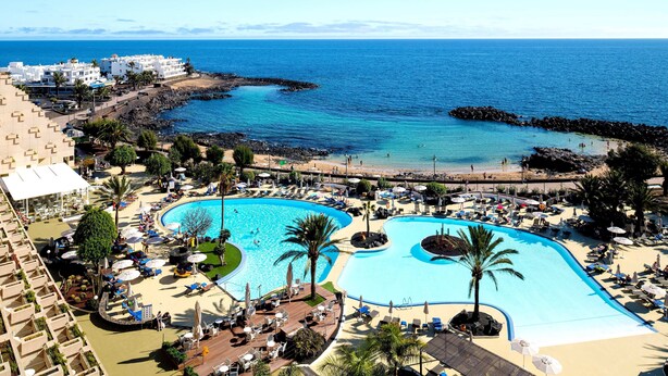 Resort com ampla área de piscina, acesso à praia e vista para o oceano.