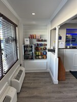 Quarto de hotel com cozinha compacta, minibar e janela com persianas.