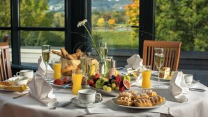 Um café da manhã servido com uma mesa para dois, com croissants, frutas, suco e taças de champanhe.