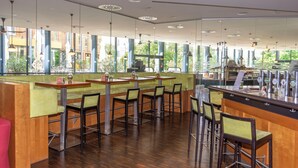 Restaurante moderno com pé-direito alto, grandes janelas e área de bar.