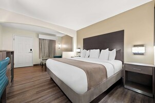 Quarto de hotel com uma cama grande, mesas de cabeceira, escrivaninha e uma cadeira.