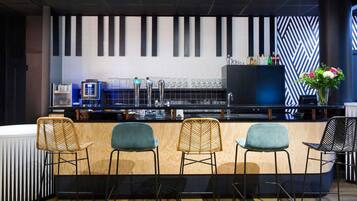 Uma área de bar com balcão, banquetas, uma televisão e uma parede decorativa.