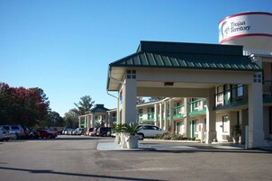 Um motel com posto de gasolina, várias vagas de estacionamento e um reservatório de água grande no telhado.