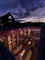 Hotel com área de terraço no telhado, iluminação de festão, vários arranjos de assento e placa da Hilton visível.