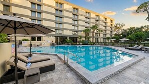 Um hotel com piscina, espreguiçadeiras e guarda-sóis.