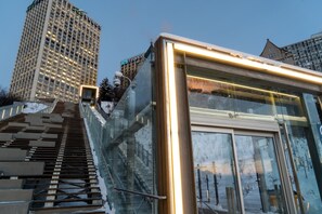 Um edifício moderno com fachada de vidro e uma escadaria que leva a uma entrada.