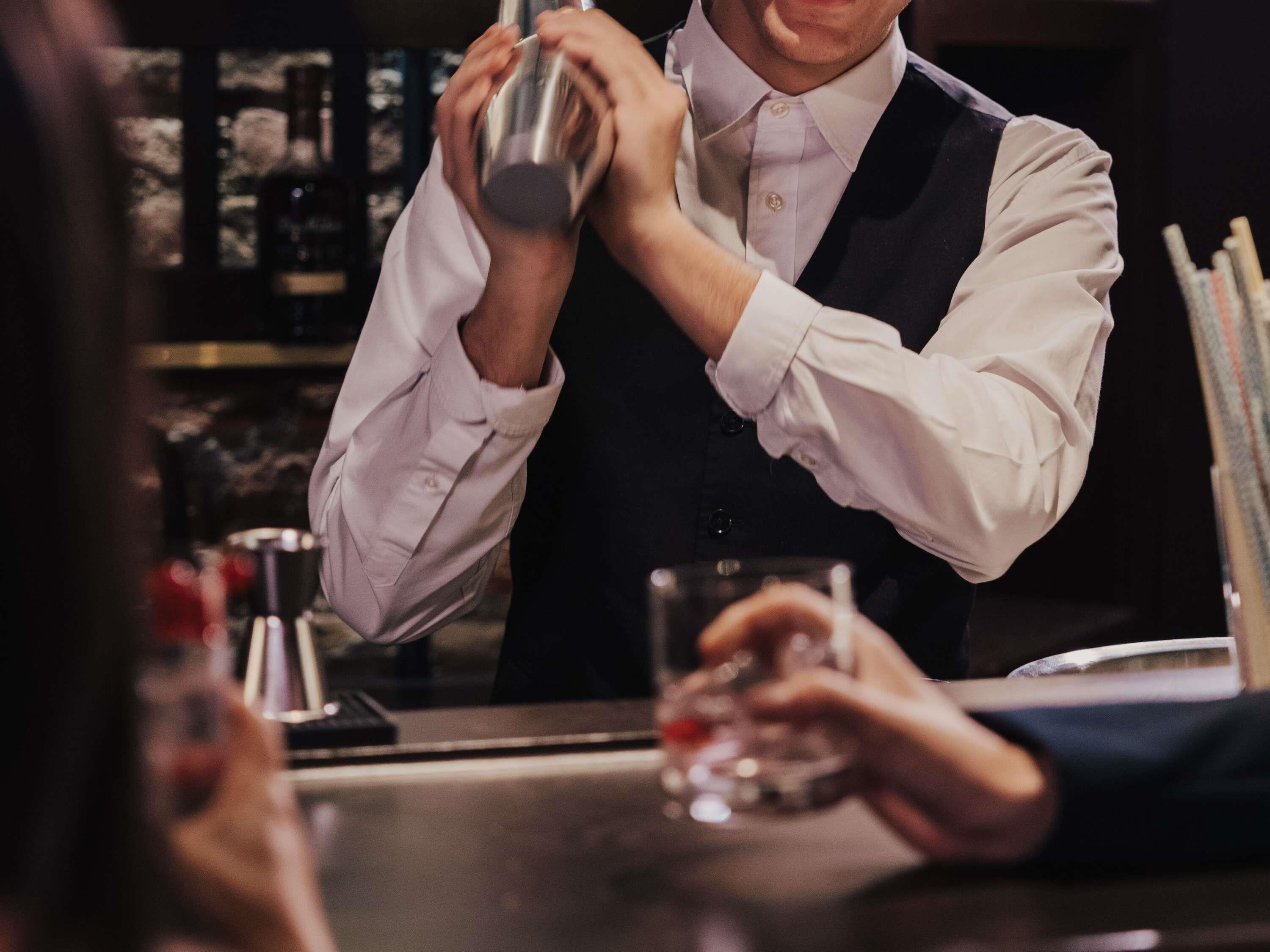 Um bartender preparando uma bebida atrás do balcão.