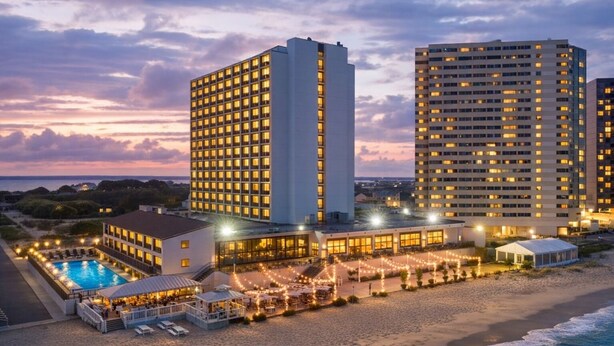 Um hotel com piscina, assentos à beira-mar e edifícios altos ao fundo.