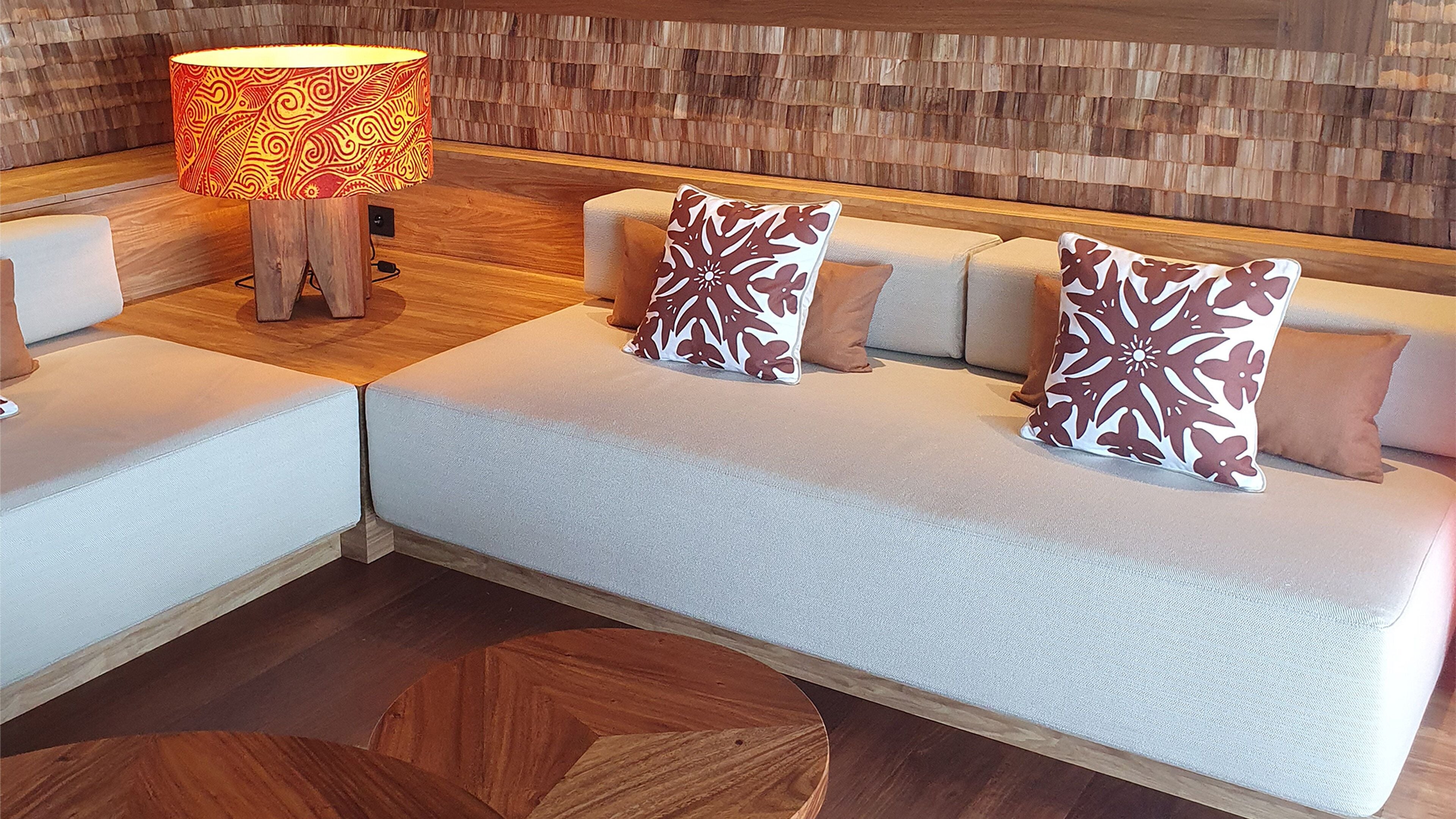 Uma sala de estar moderna com sofá seccional, almofadas decorativas estampadas, mesa de centro de madeira e parede com textura.