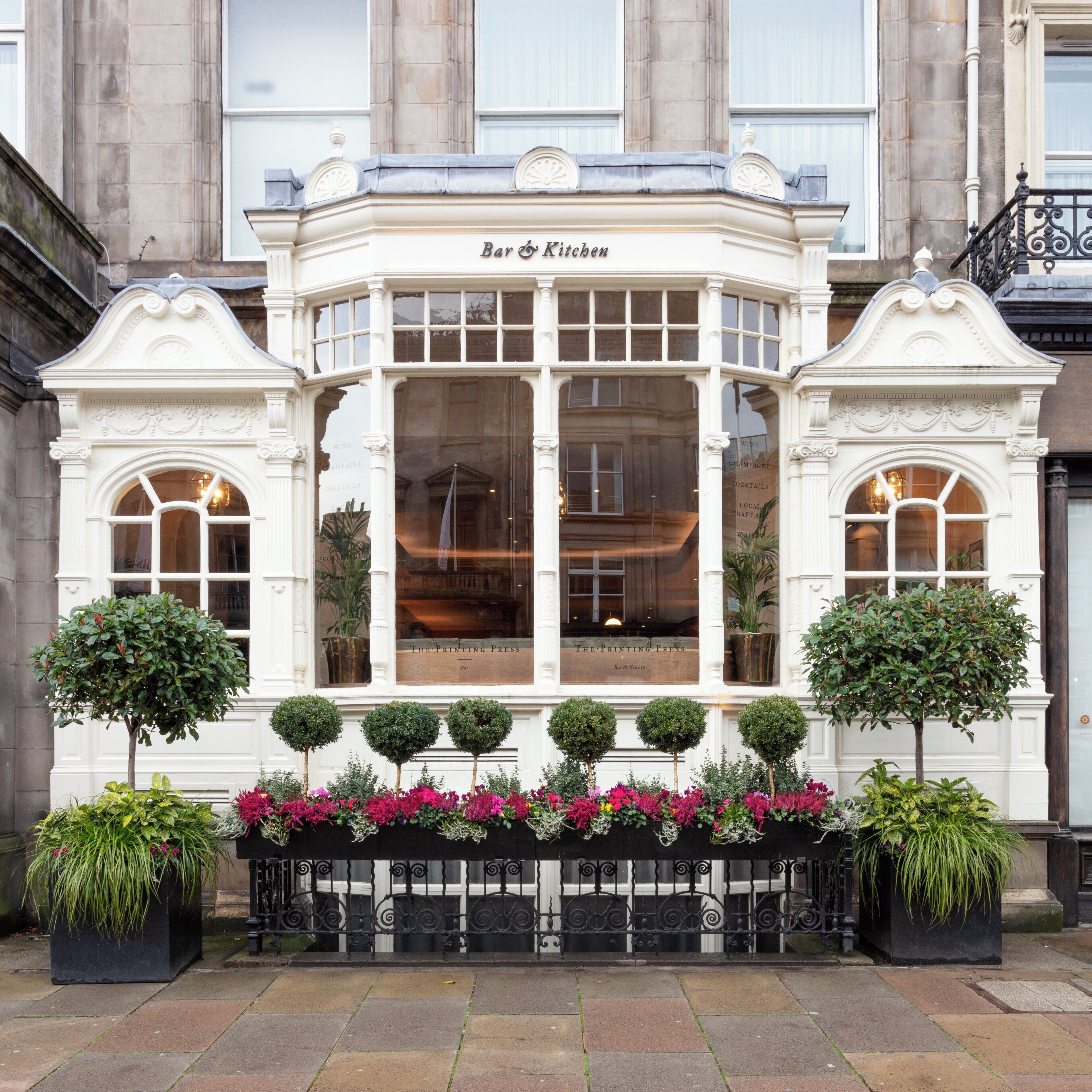 Edifício com placa indicando 'Bar & Kitchen' e vitrine exibindo 'The Printing Press Bar & Kitchen'.