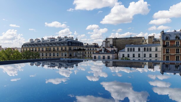 Uma cidade histórica europeia com arquitetura clássica refletida em águas calmas.