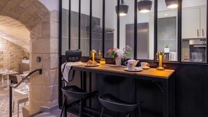Uma cozinha moderna com um arco de pedra, bancada de madeira, cadeiras pretas e um espelho grande.