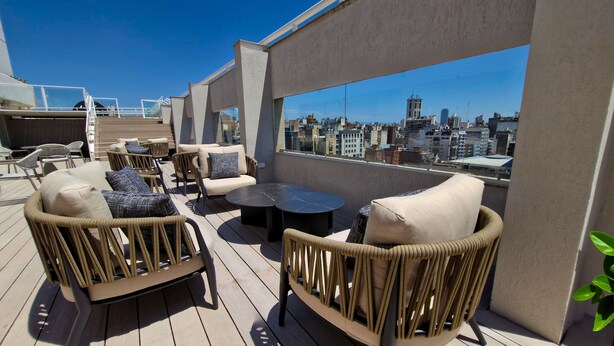 Terraço no terraço com móveis de vime, uma mesa redonda e vista para a cidade.