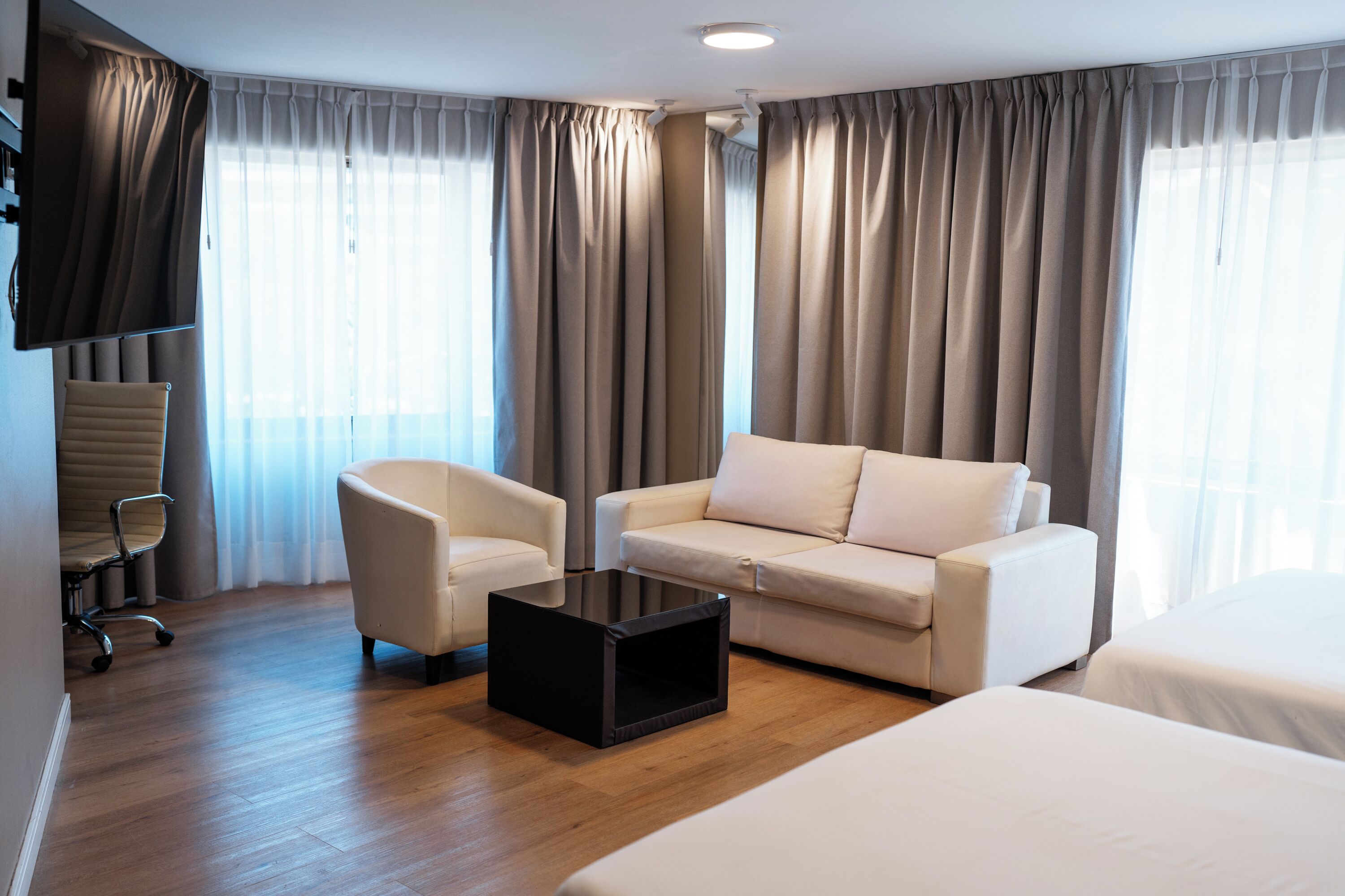 Quarto de hotel com sofá, poltrona e uma cama.