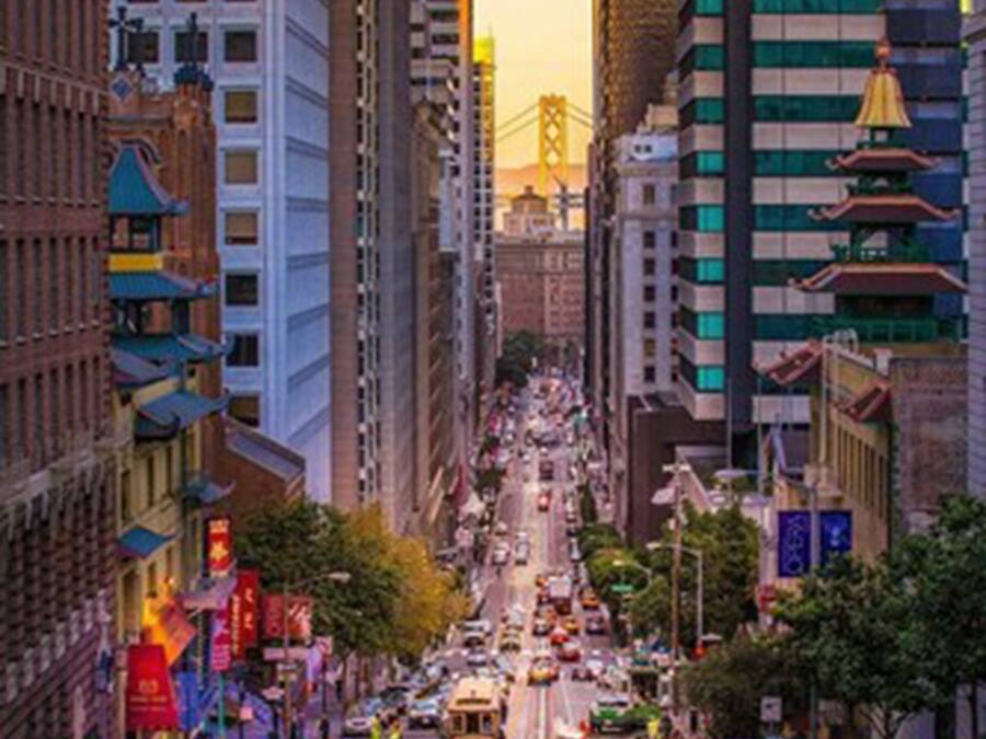 Uma rua com linhas de bonde, edifícios e carros estacionados.