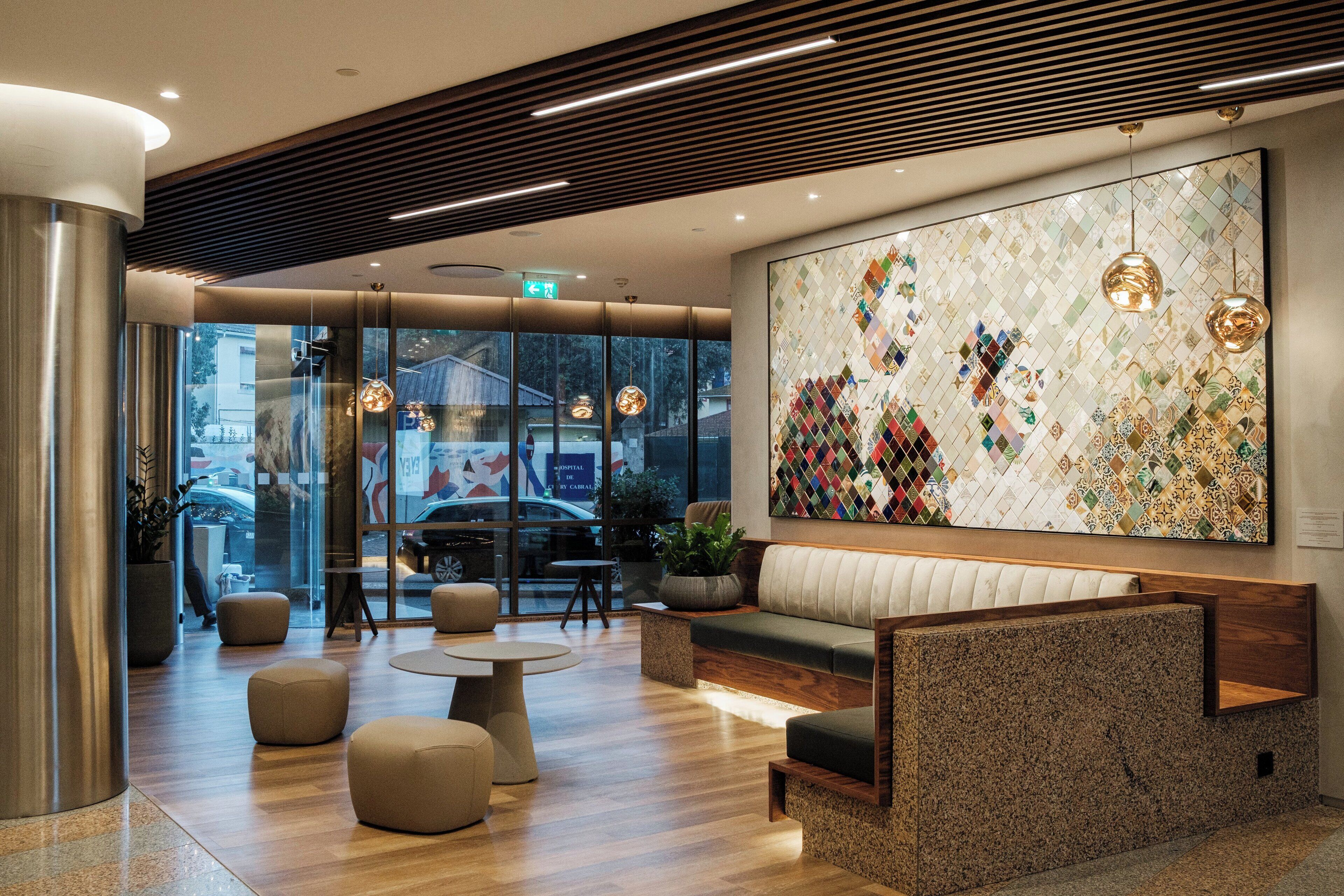 Um lobby moderno com área de estar, janelas amplas e um mural abstrato colorido.