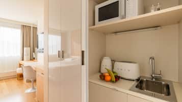 Quarto de hotel moderno com cozinha compacta, incluindo micro-ondas, torradeira e pia.
