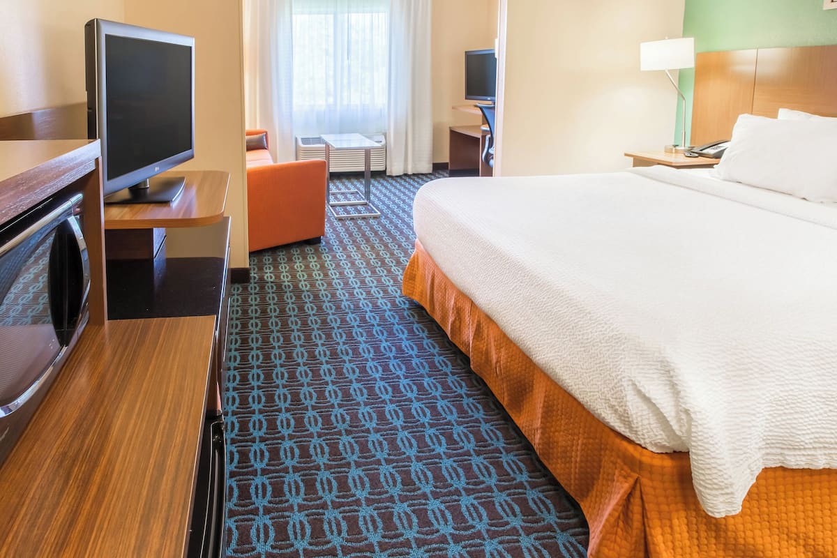 Quarto de hotel com uma cama, televisão, escrivaninha e uma cadeira.