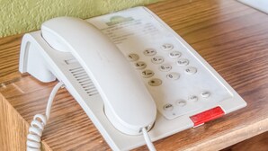 Um telefone branco sobre uma mesa de madeira com um cabo enrolado.