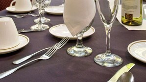 Mesa de jantar posta com guardanapos brancos, copos de vinho e uma garrafa de vinho.