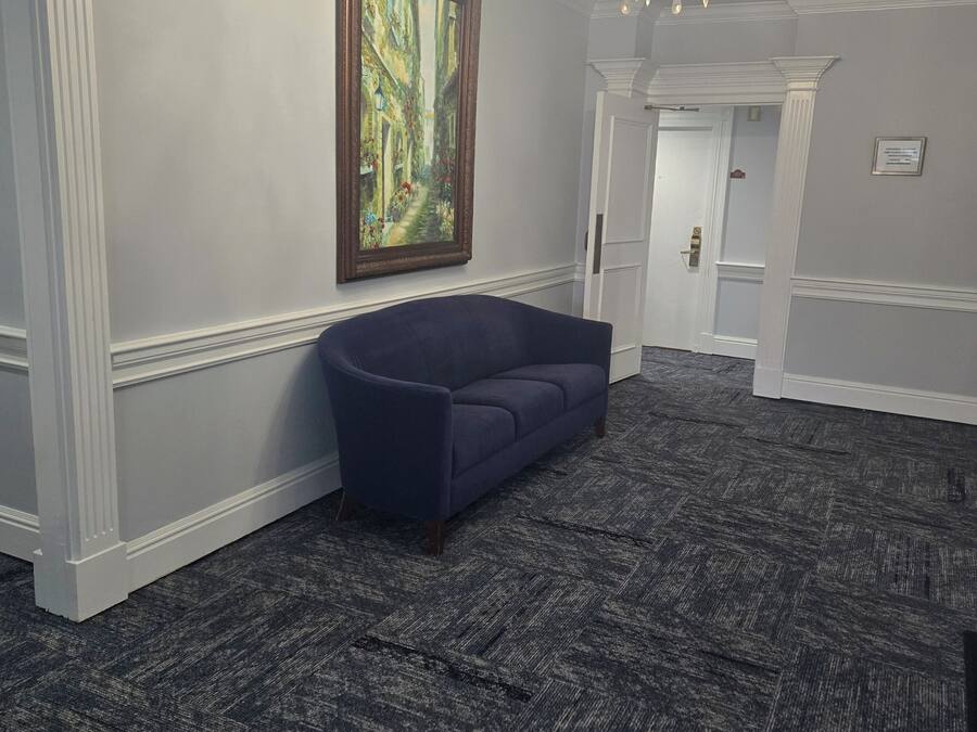 Um quarto com um sofá azul escuro, um candelabro e uma pintura na parede.