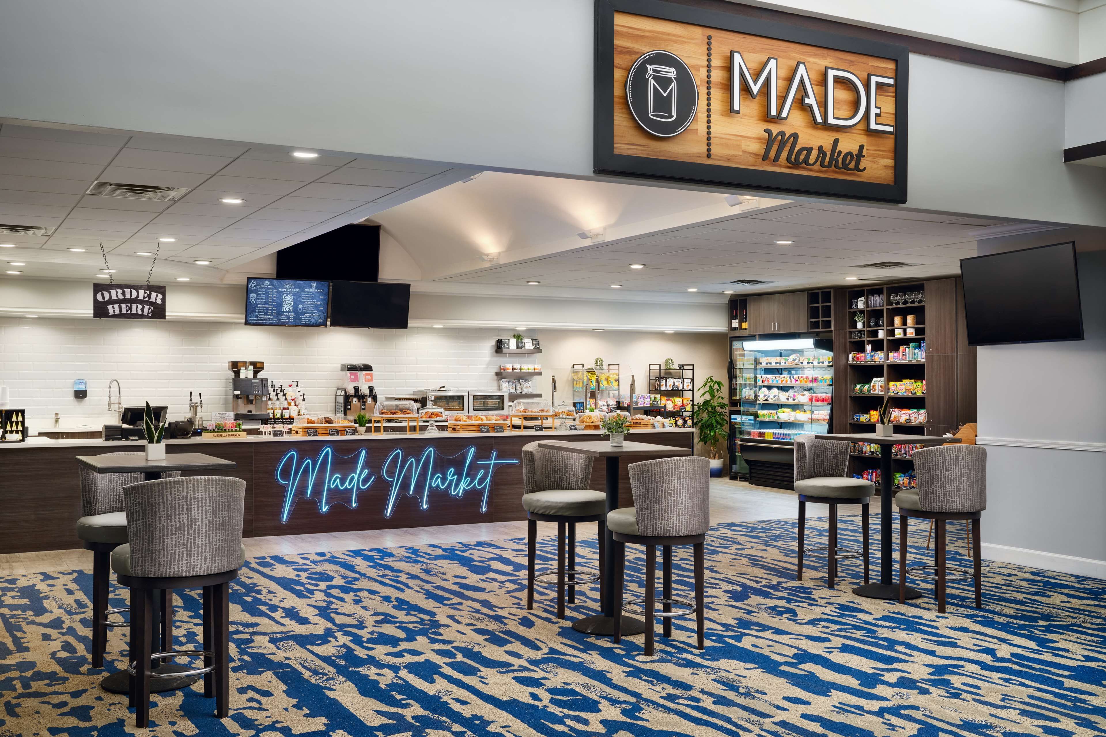 Um café da Made Market com área de bar, assentos e exposição de alimentos.