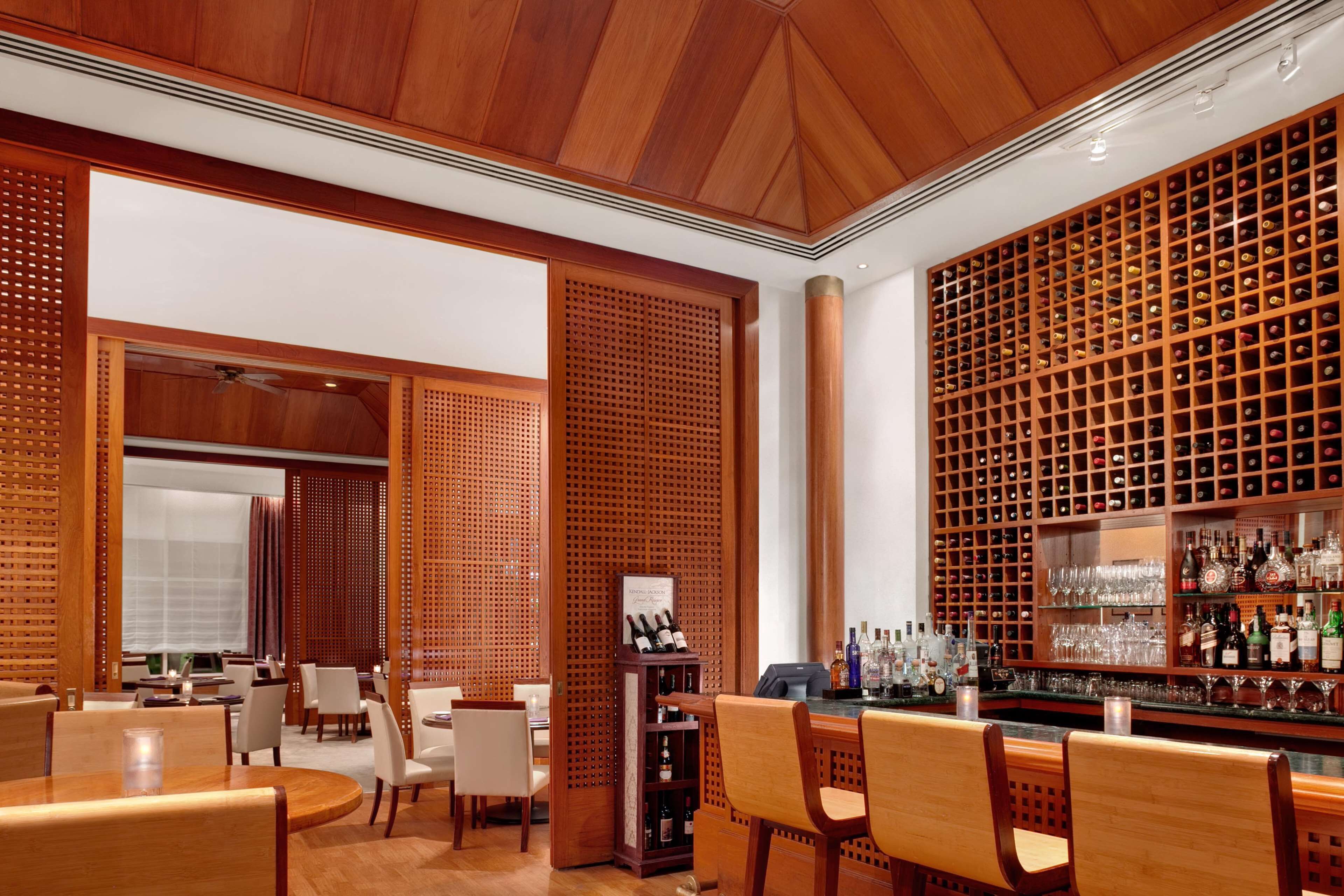 Uma área de bar com mobiliário de madeira, um suporte para vinhos e um balcão com garrafas e copos.
