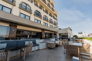 Bar no terraço com mesas ao ar livre, área de bar e vista para a fachada do edifício.