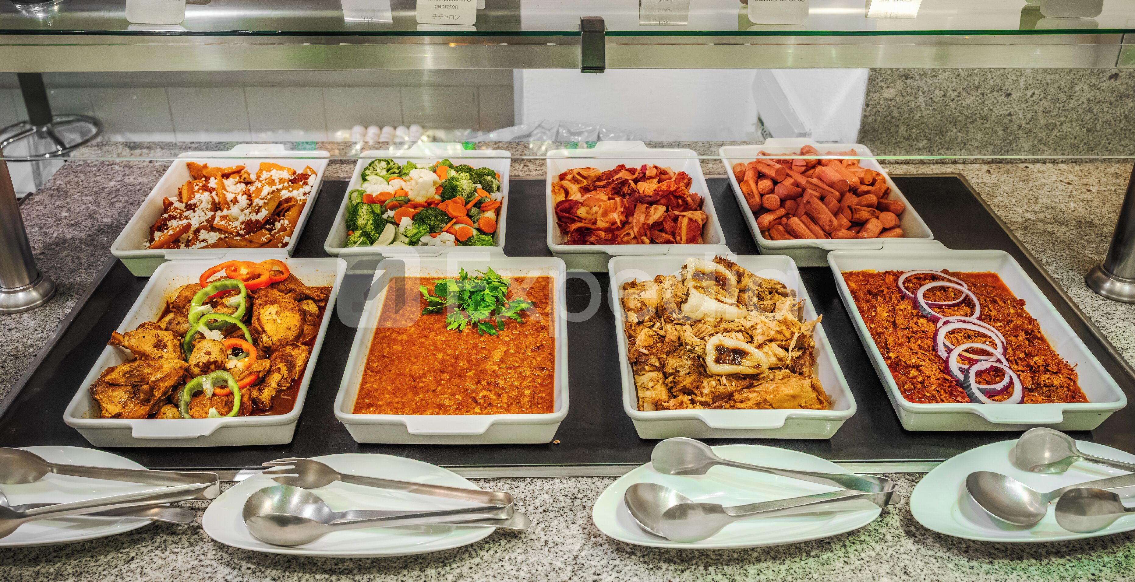 Buffet com diversos pratos, incluindo carnes, legumes e saladas.