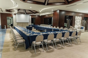 Uma sala de conferência com uma mesa comprida, cadeiras e um projetor.