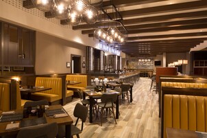 Um restaurante com cabines e mesas, uma área de bar e teto trabalhado.