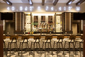 Uma área de bar com parede de tijolos, ripas de madeira e um letreiro de neon com números.