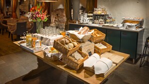 Um buffet de café da manhã com diversos pães, doces e bebidas.