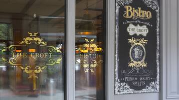 Uma janela com um letreiro indicando 'Bistro The Croft' e uma placa emoldurada que diz 'Espíritos de Qualidade Premium'.